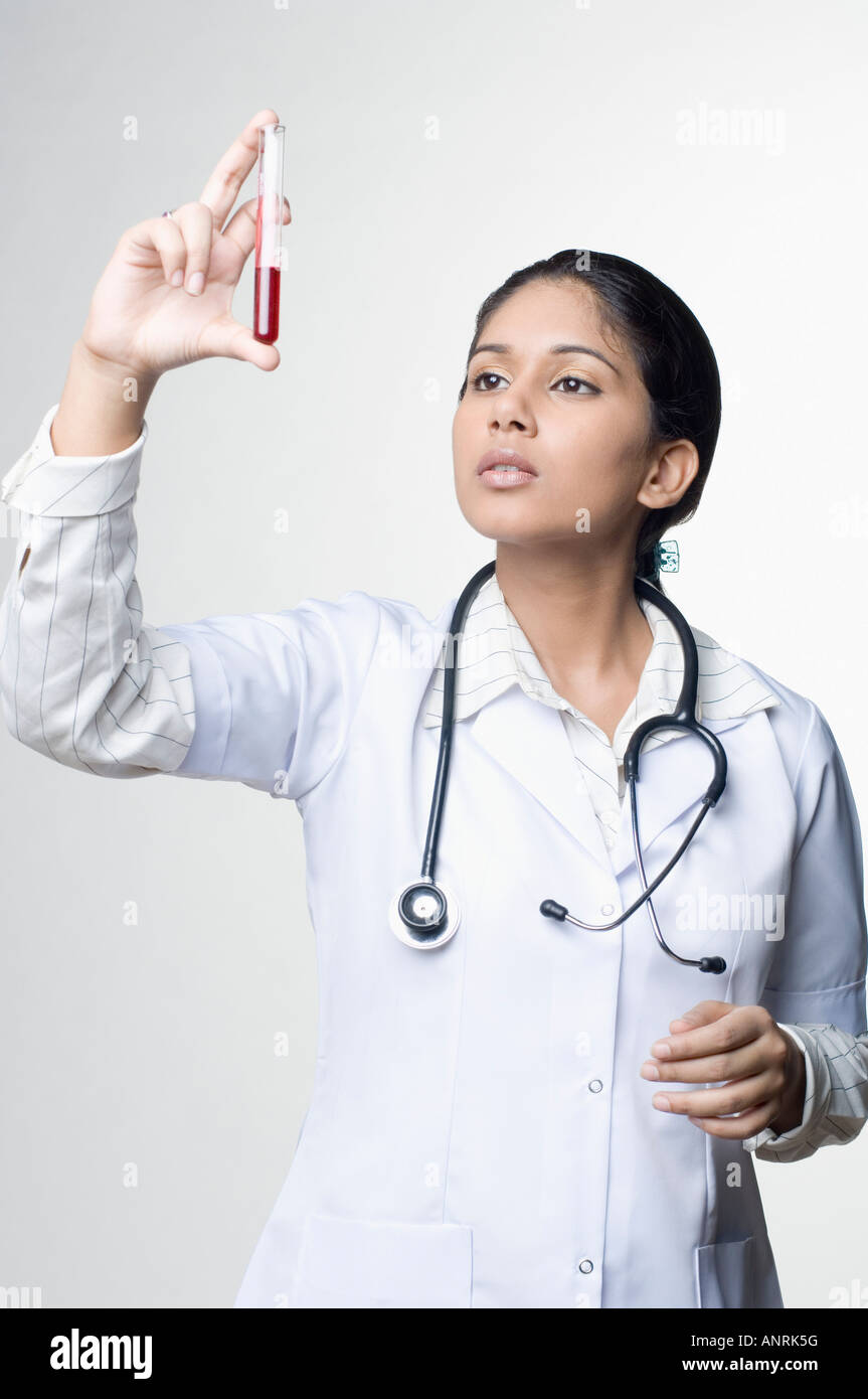 Close-up of a female doctor looking at a test tube of blood sample ...