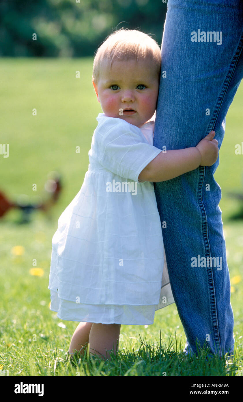Little girl holding on to her mothers leg Stock Photo - Alamy