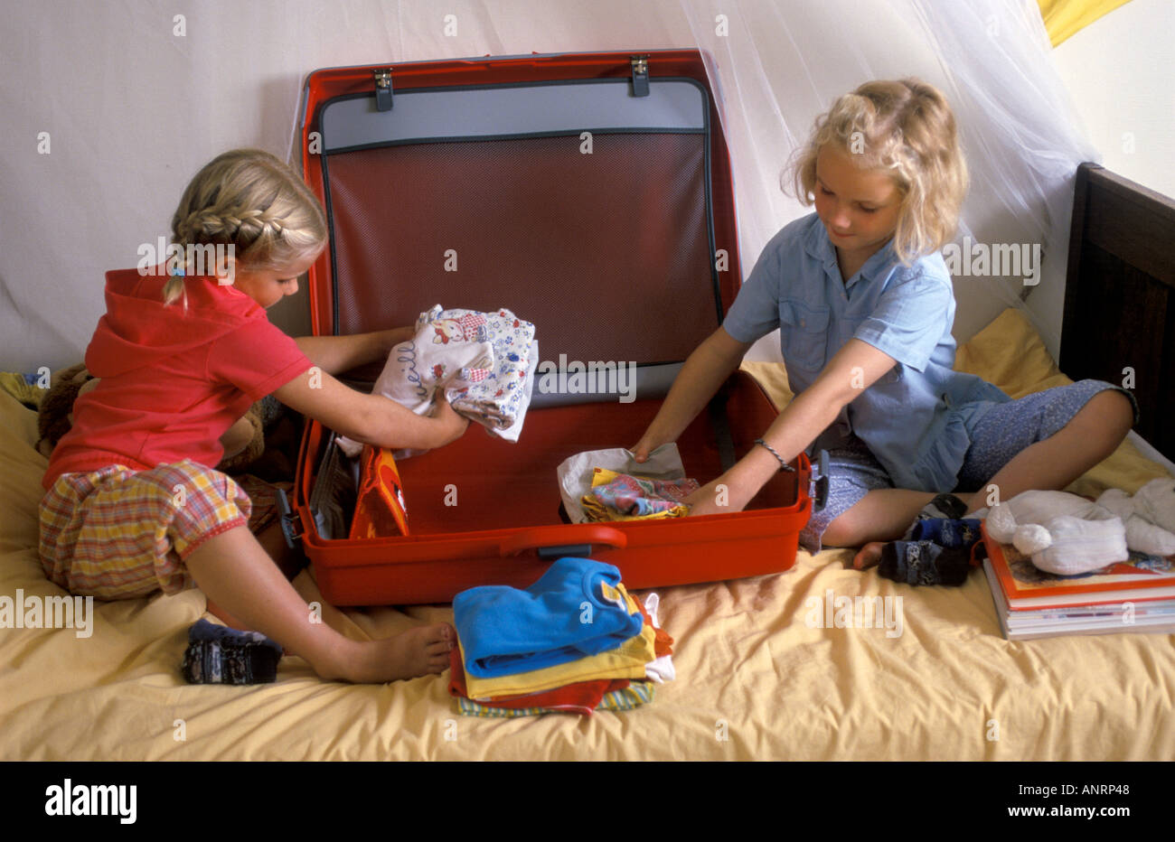 Two girls packing a suitcase for vacation Stock Photo - Alamy