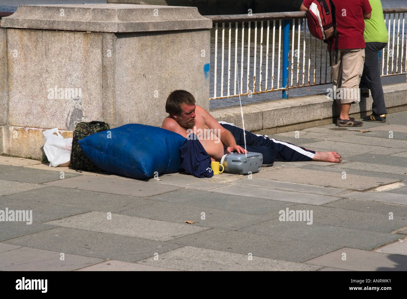 a homeless man lying on the pavement on the south bank of the River ...