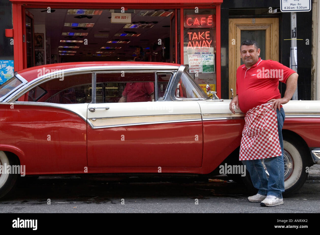 An old red American classic car outside a diner with the chef wearing ...
