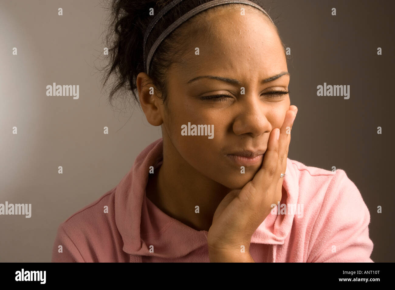 dark skinned young girl suffering from toothache, rubbing her cheek for ...