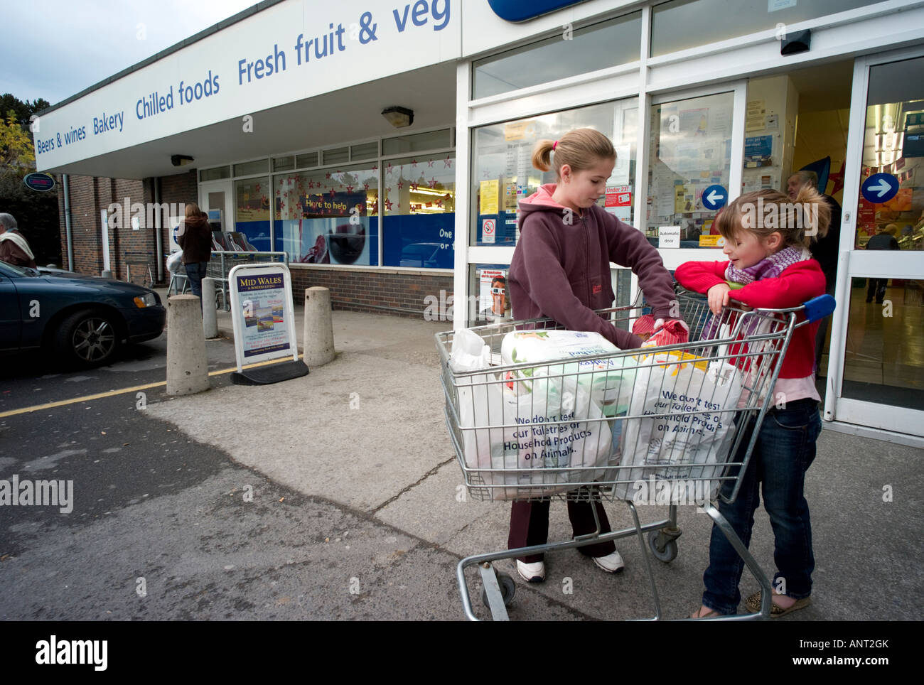 Two children with shopping trolley of food, outside Co-Op supermarket ...