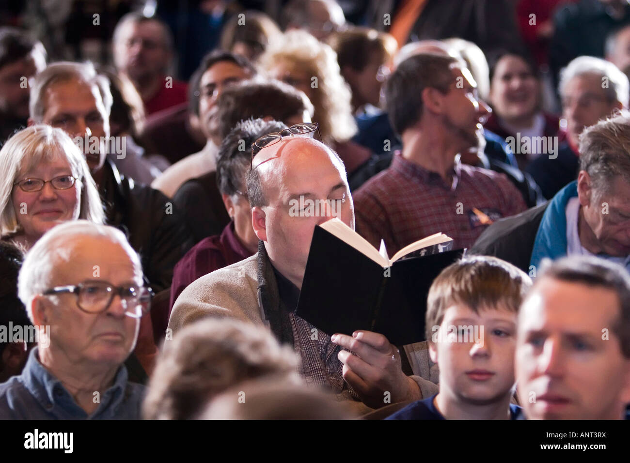 Man in crowd reads a book Stock Photo - Alamy