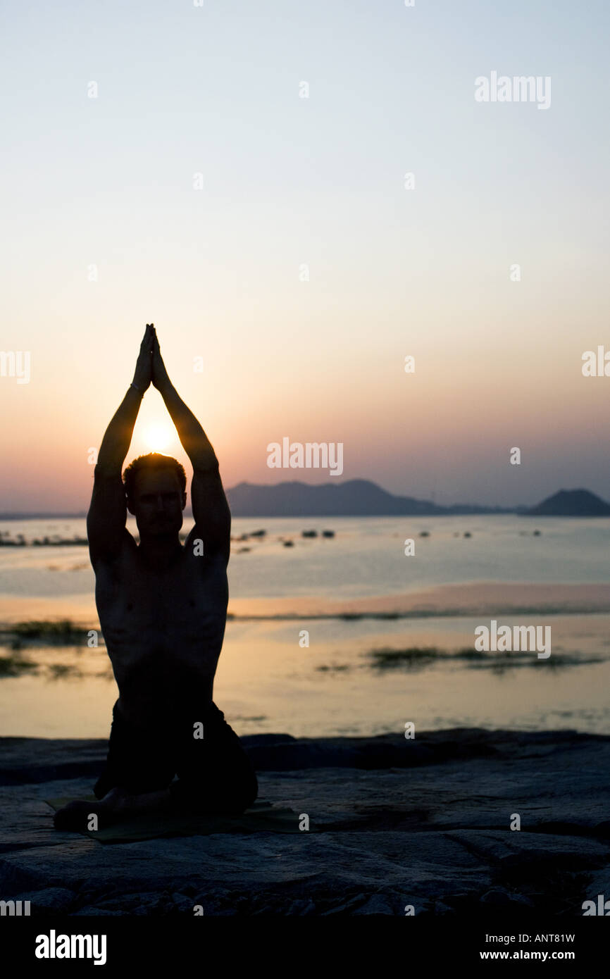 Silhouette of a man performing Hatha Yoga ardha kapotasana half pigeon ...