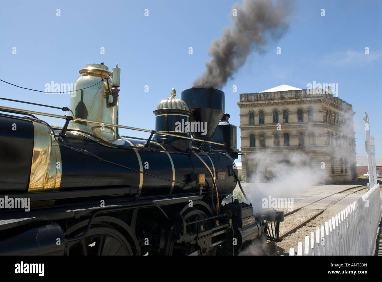 Restored steam train steams past a historic whitestone building in the ...