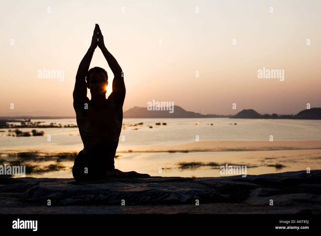 Silhouette of a man performing Hatha Yoga ardha kapotasana half pigeon ...