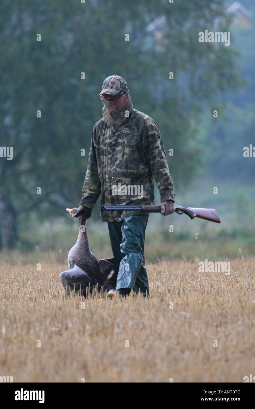 Hunter with dead goose and rifle in his hand Stock Photo - Alamy