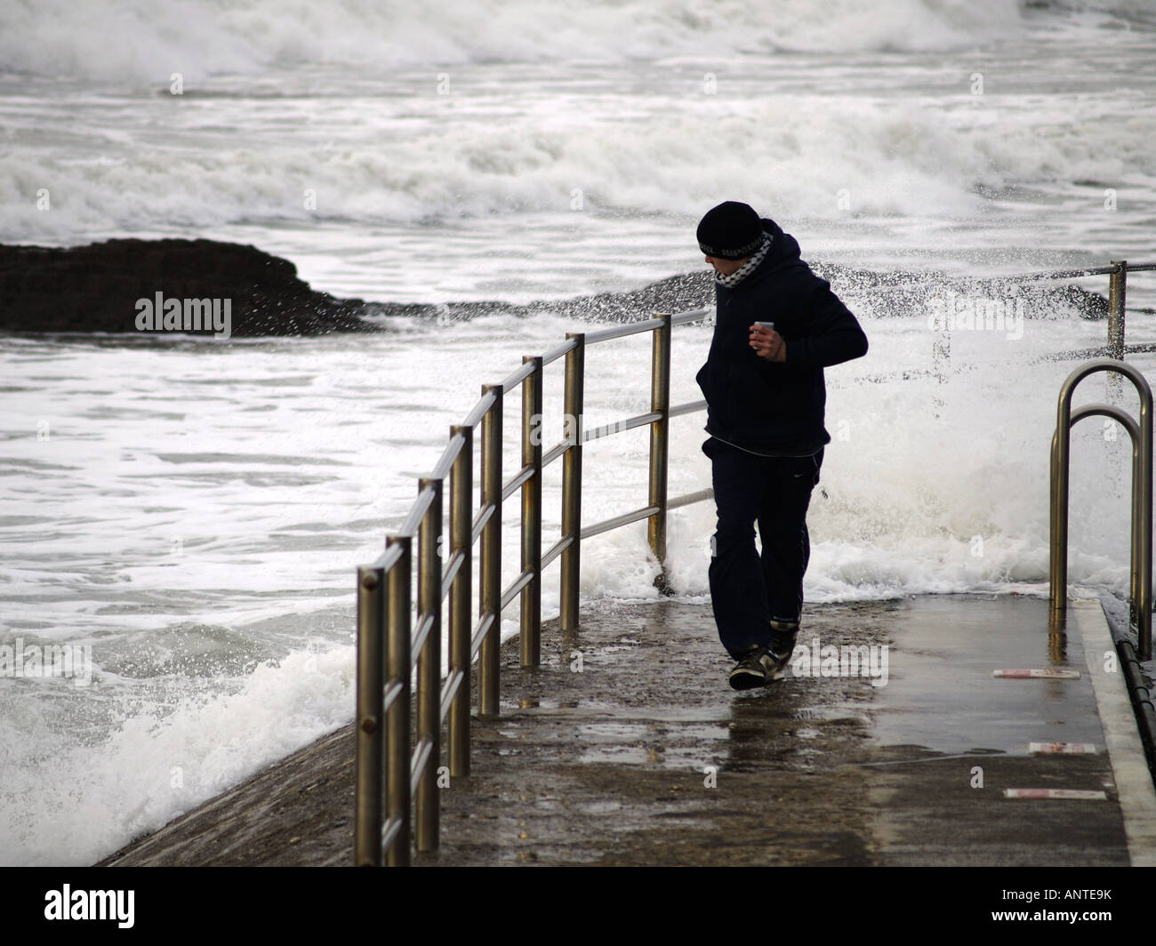 Teenage boy running around the edge of Bude outdoor sea pool, trying ...