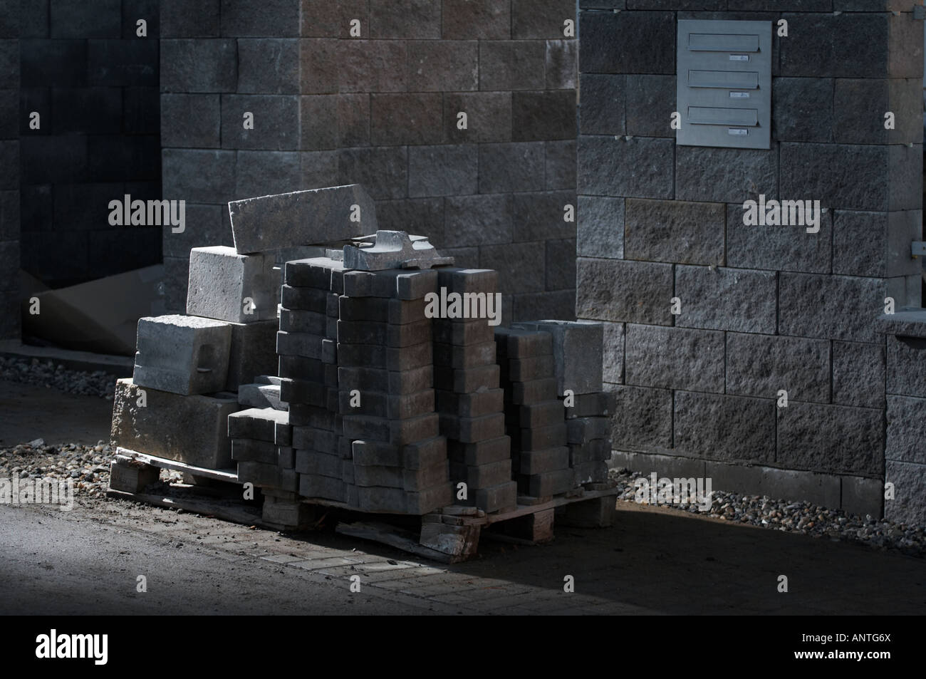 Stacked concrete paving blocks and bricks on a wooden pallet in an industrial setting, ready for ...