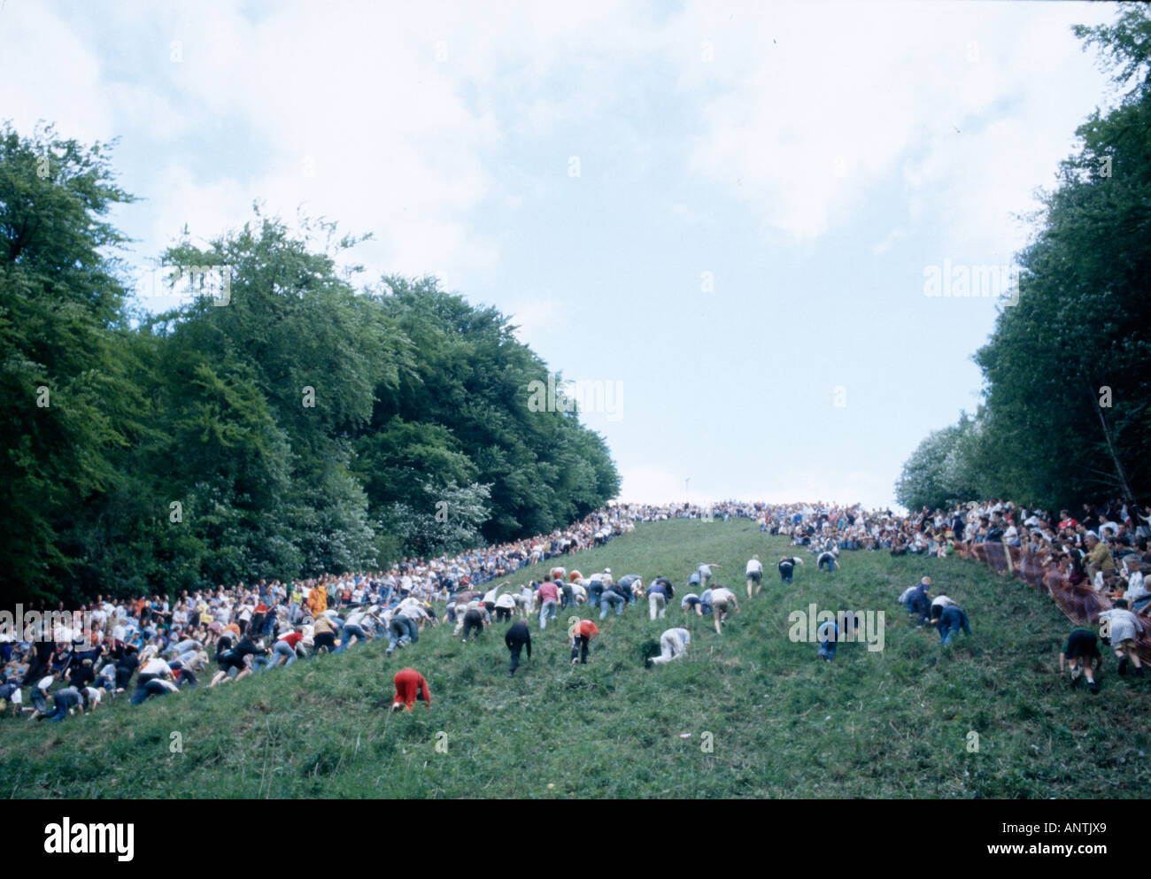GROUP OF PEOPLE RUNNING UP HILL AFTER CHEESE ROLL Stock Photo - Alamy
