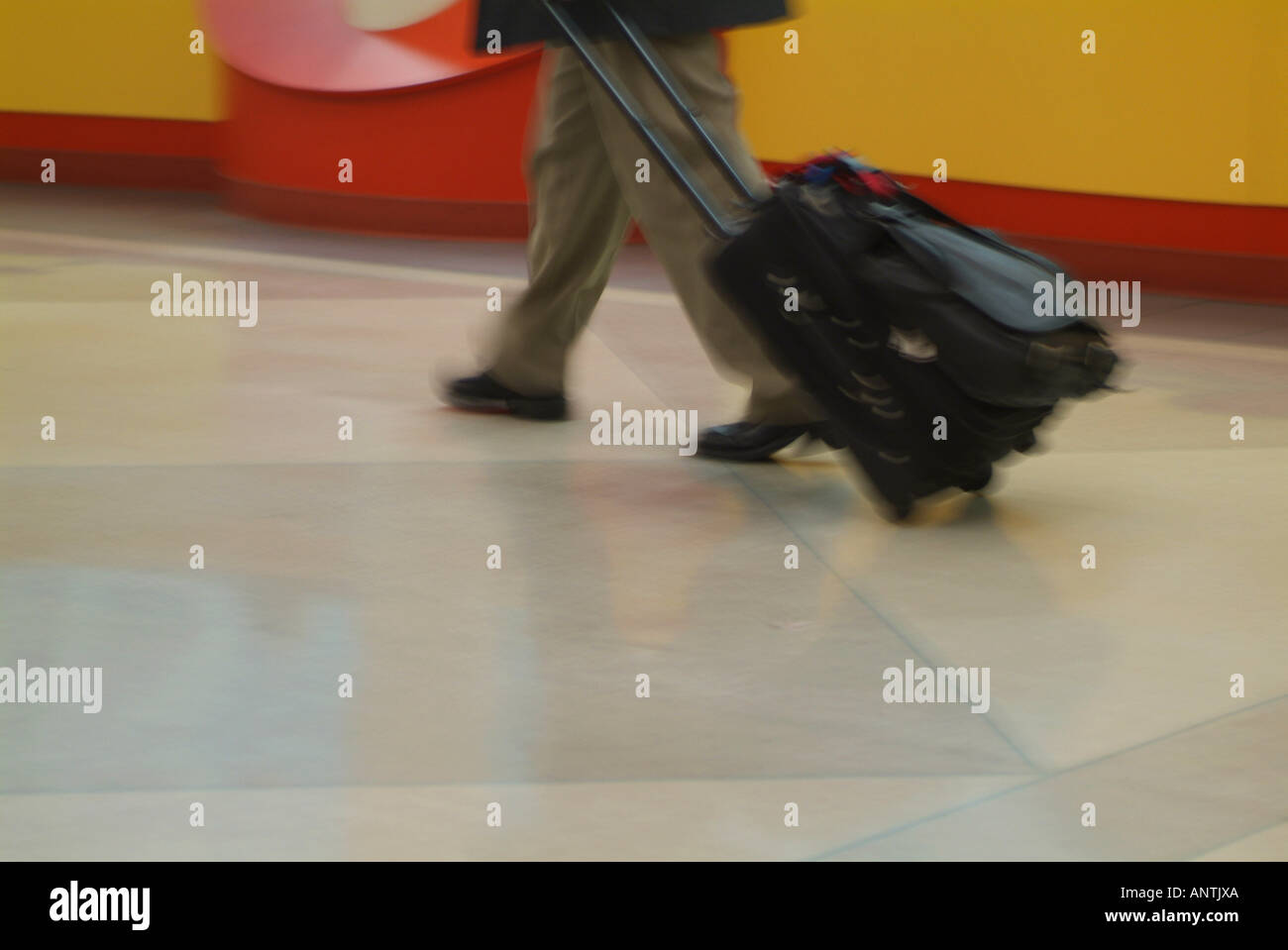 A traveler rushing through an airport pulling their personal luggage ...