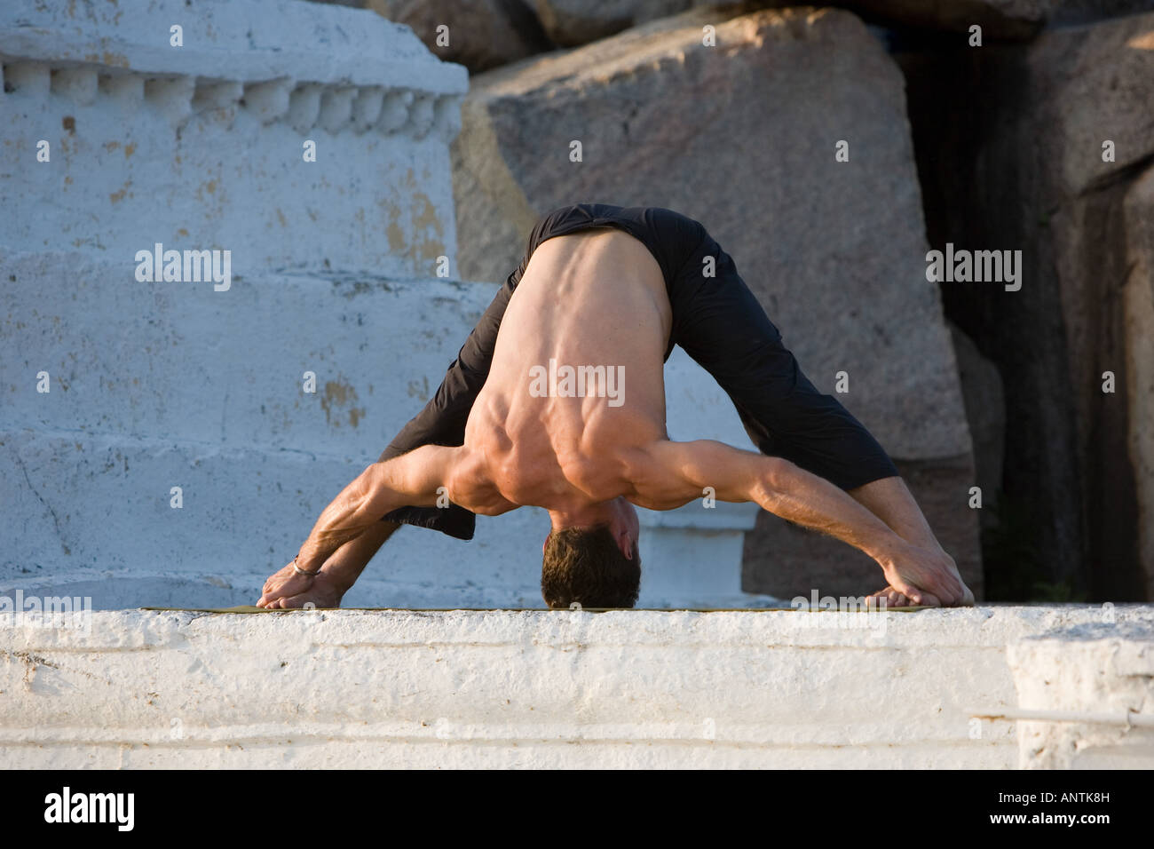 Man performing Hatha Yoga forward stretch pose on a hindu temple in ...