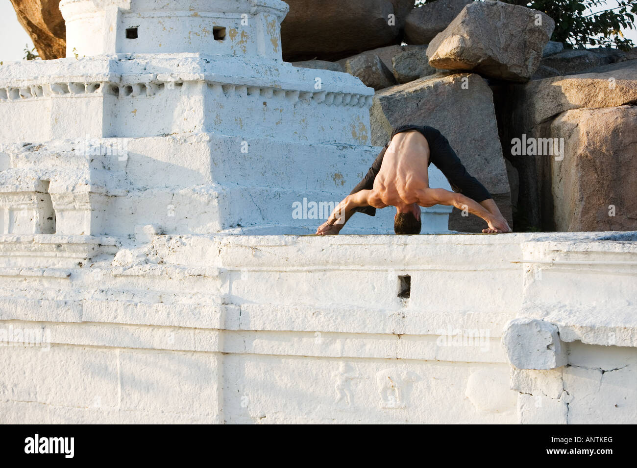 Man performing Hatha Yoga forward stretch pose on a hindu temple in ...