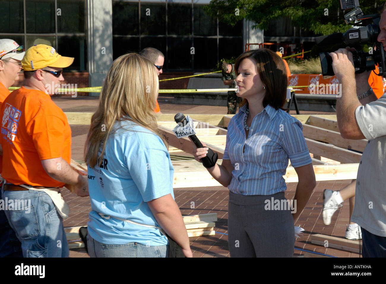 TV News reporter interviews volunteers who are building a home for a ...