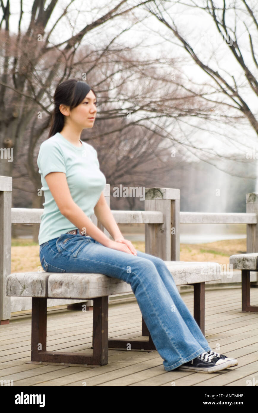 Young woman sitting on bench Stock Photo - Alamy