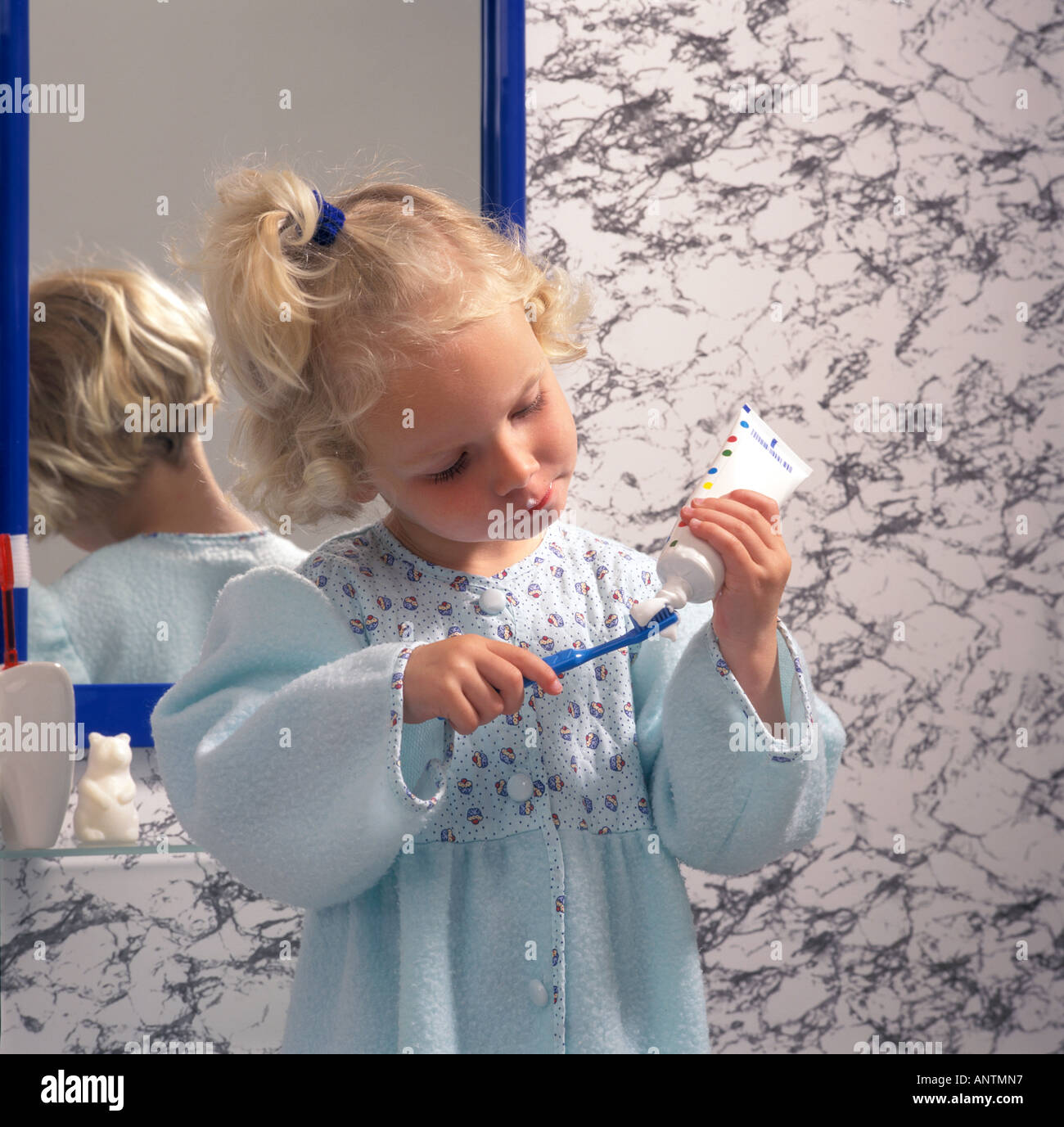Little girl is putting toothpaste on her toothbrush Stock Photo - Alamy