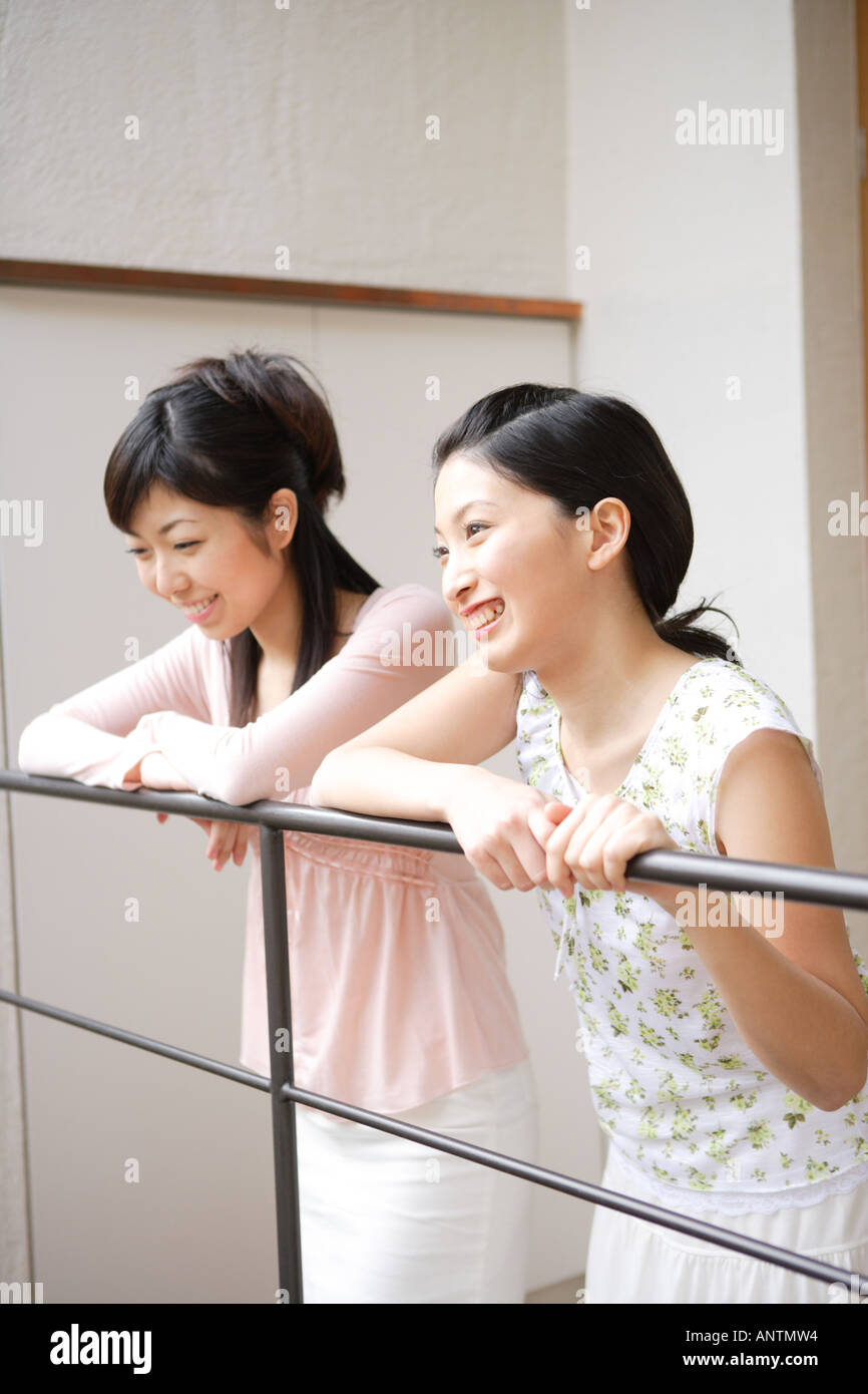 Two young women leaning on railing Stock Photo - Alamy