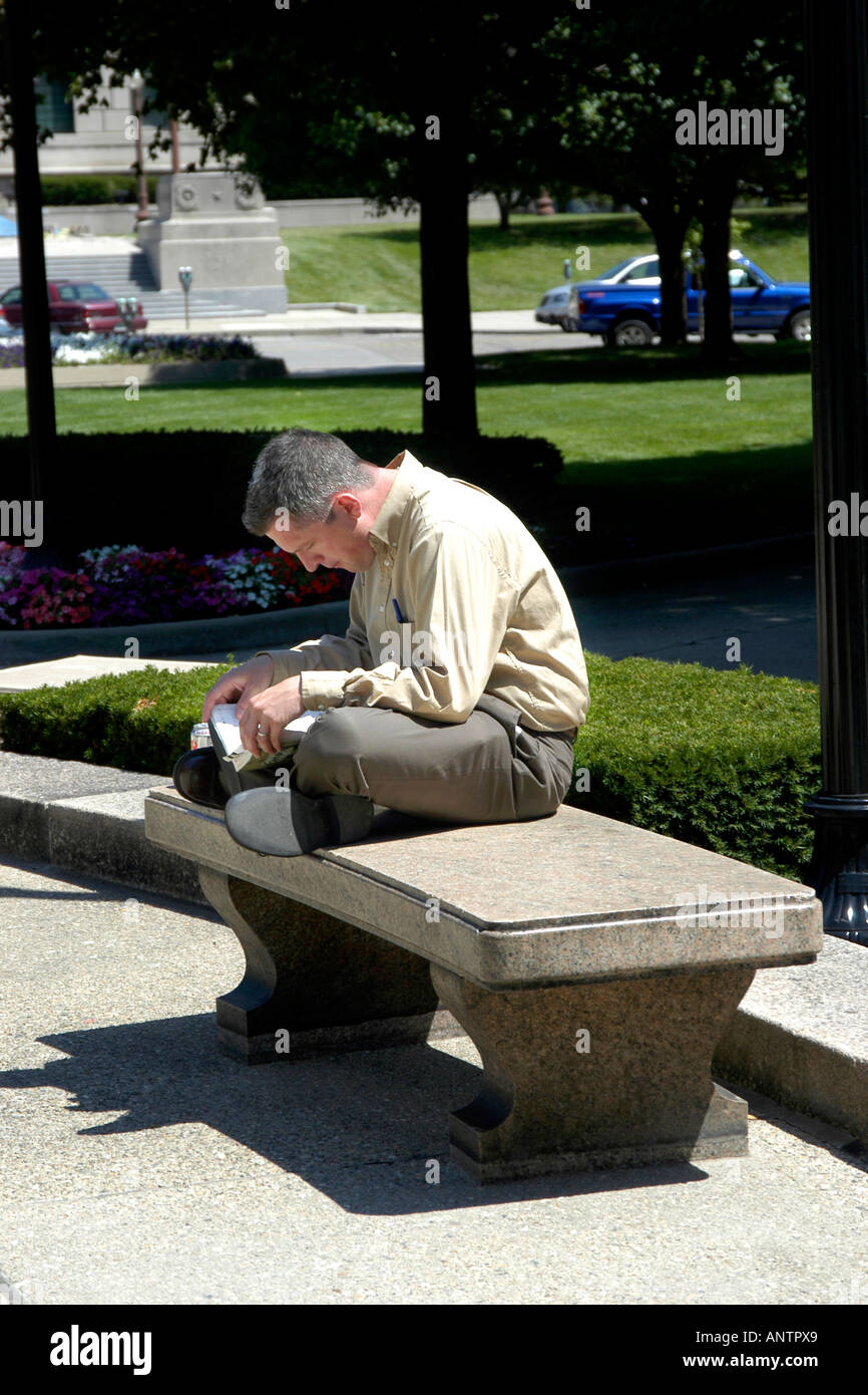 Man sitting reading and eating snacks during his lunch break in ...