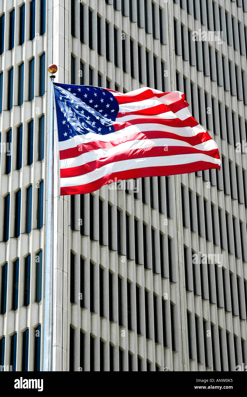 The American flag flying high in front of a skyscraper in downtown ...