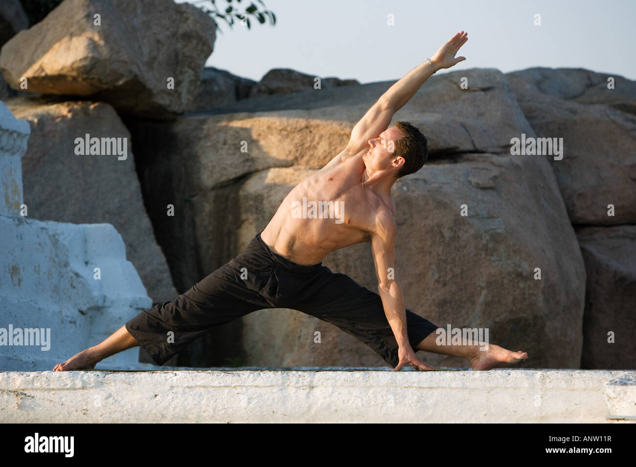 Man performing Hatha Yoga side stretch on a hindu temple in India Stock ...