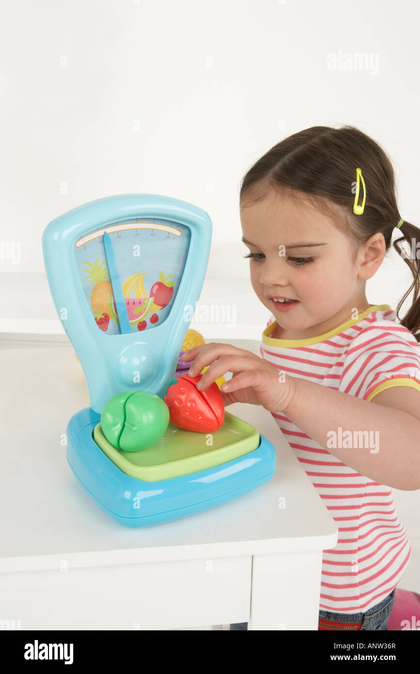 a girl plays with toy scales as she weighs toy fruit Stock Photo - Alamy
