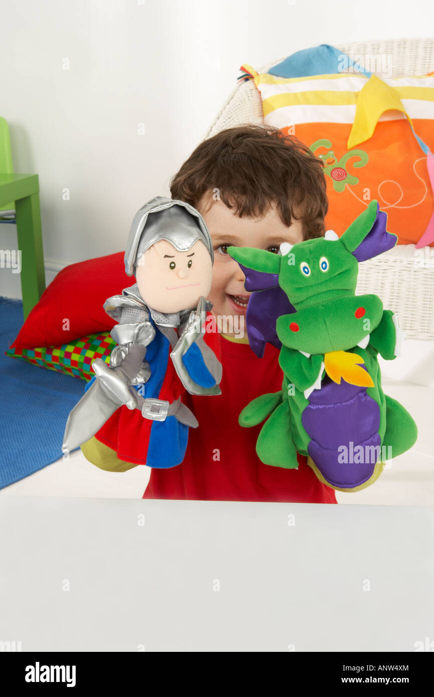 a boy smiles as he plays with a knight and a dragon hand puppet Stock ...