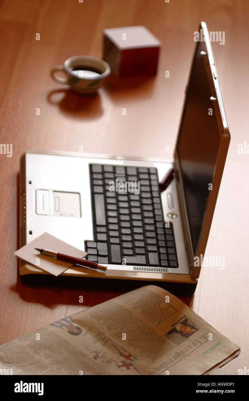 Early morning laptop computer on wooden floor with ink pen newspaper ...