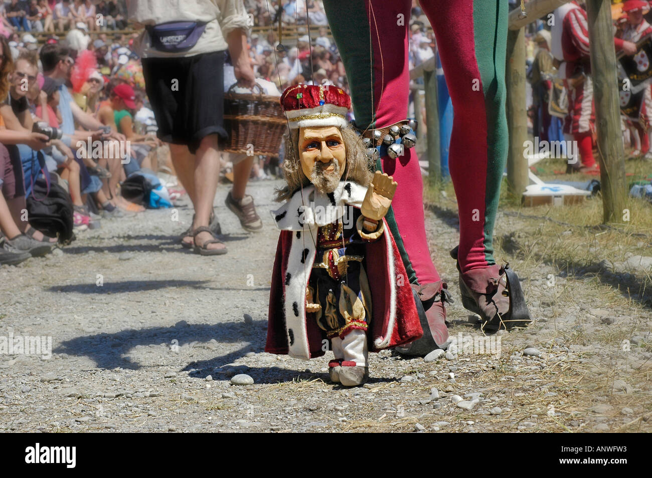 Puppet player in mediaeval medieval costume holding little marionette ...