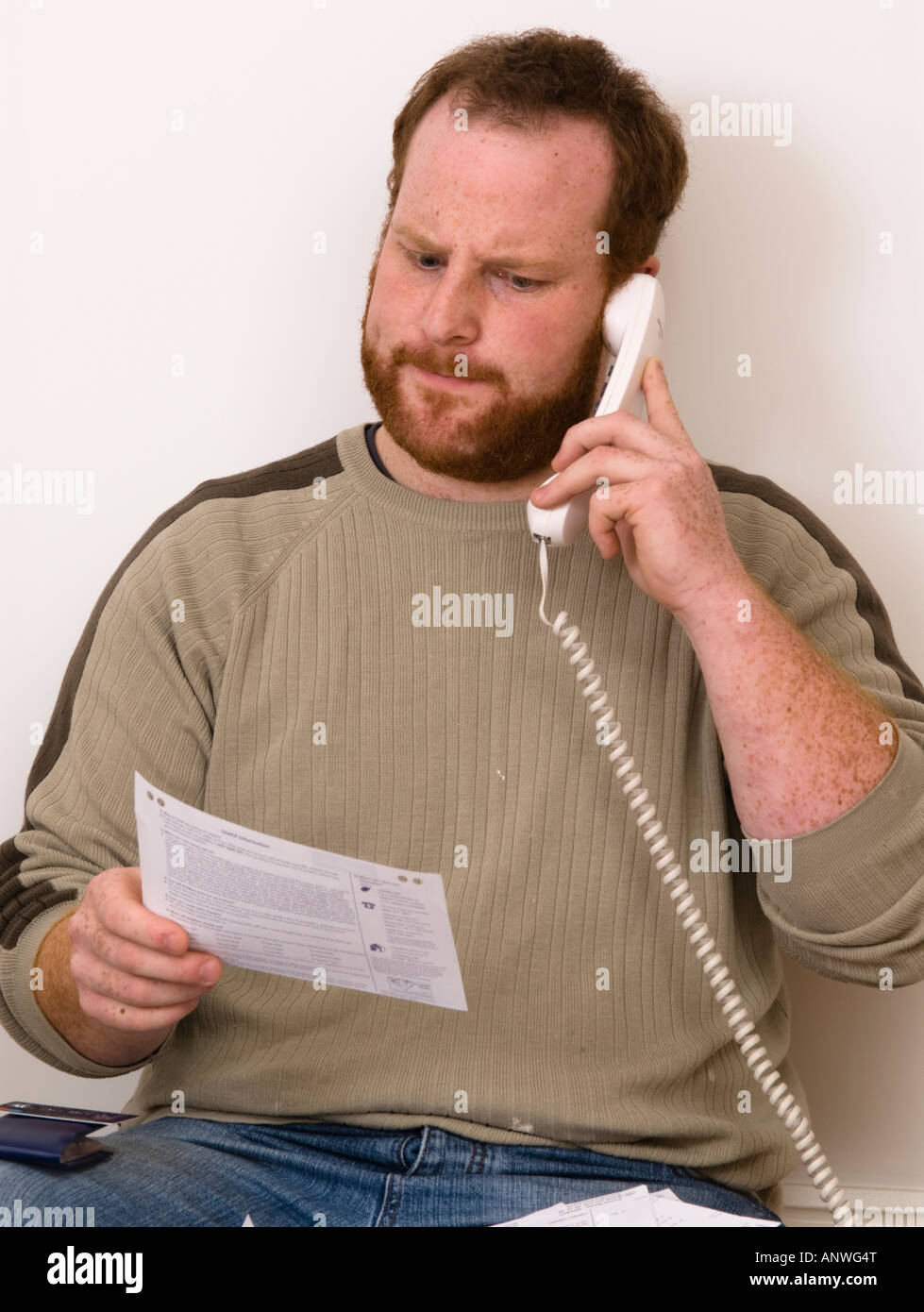 man on phone questioning items on bank statement with puzzled ...