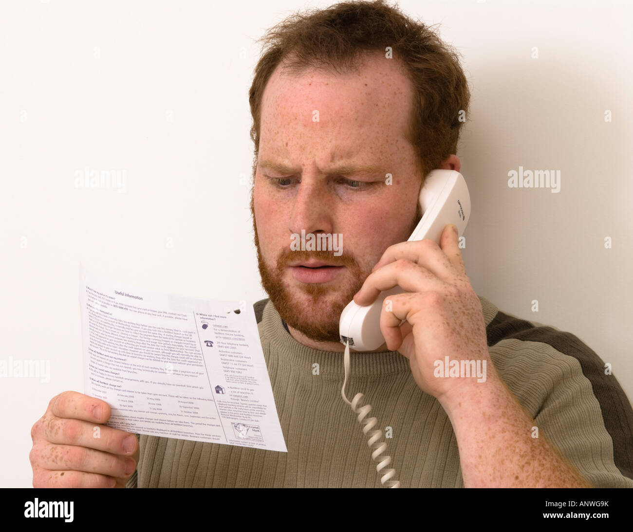 man on phone questioning items on his bank statements showing startled ...