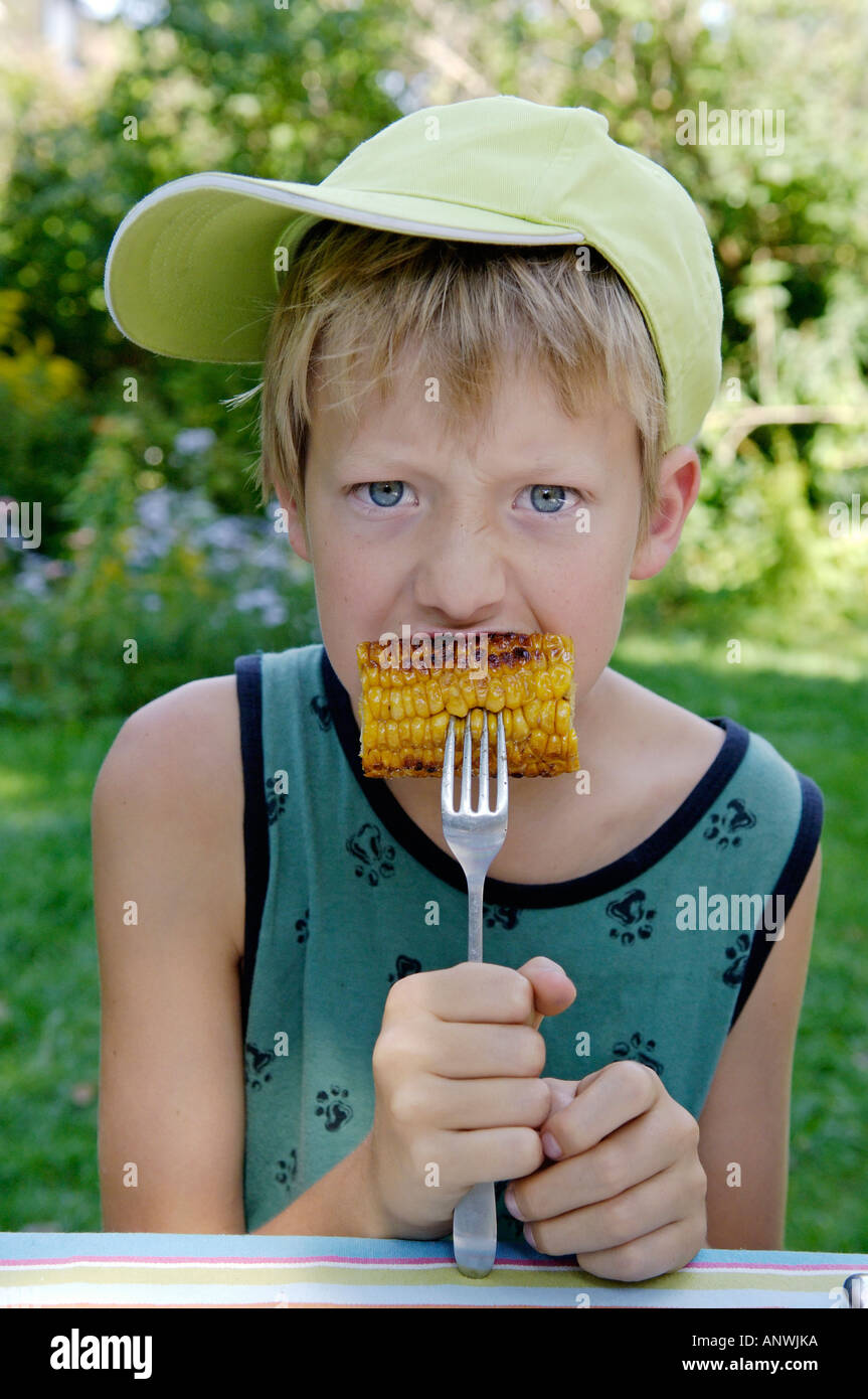 Boy, eleven-year-old, is eating fried or grilled maize corn Stock Photo ...