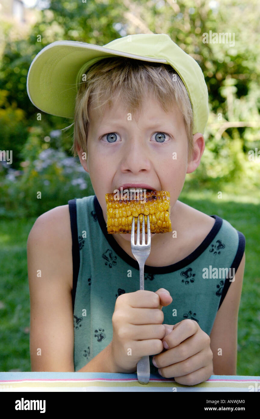 Boy, eleven-year-old, is eating fried or grilled maize corn Stock Photo ...