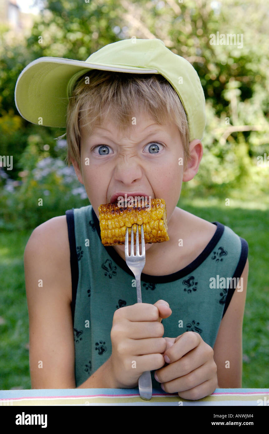 Boy, eleven-year-old, is eating fried or grilled maize corn Stock Photo ...