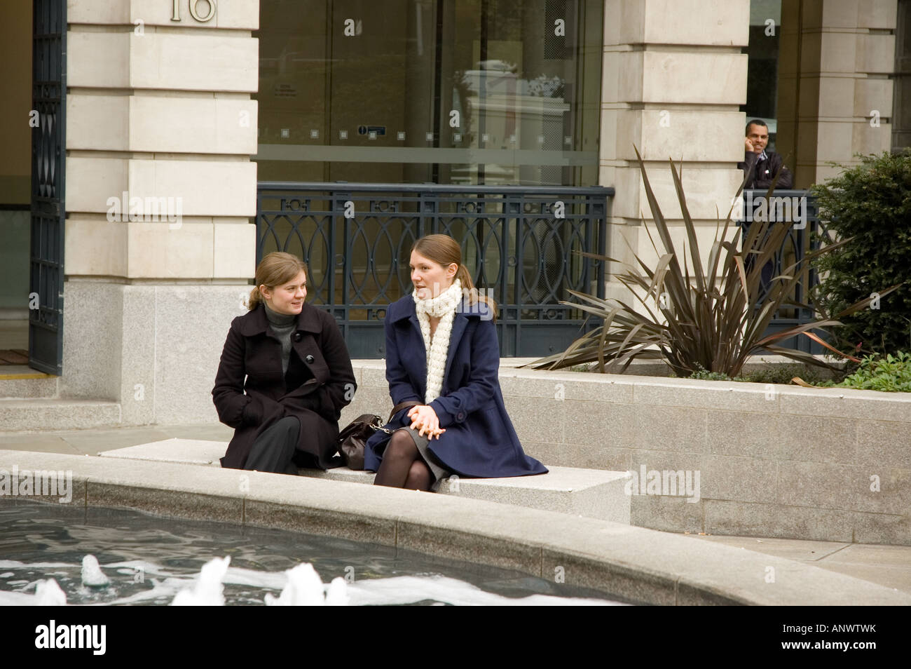 two female friend talk together sit on a bench near a fountain,london ...