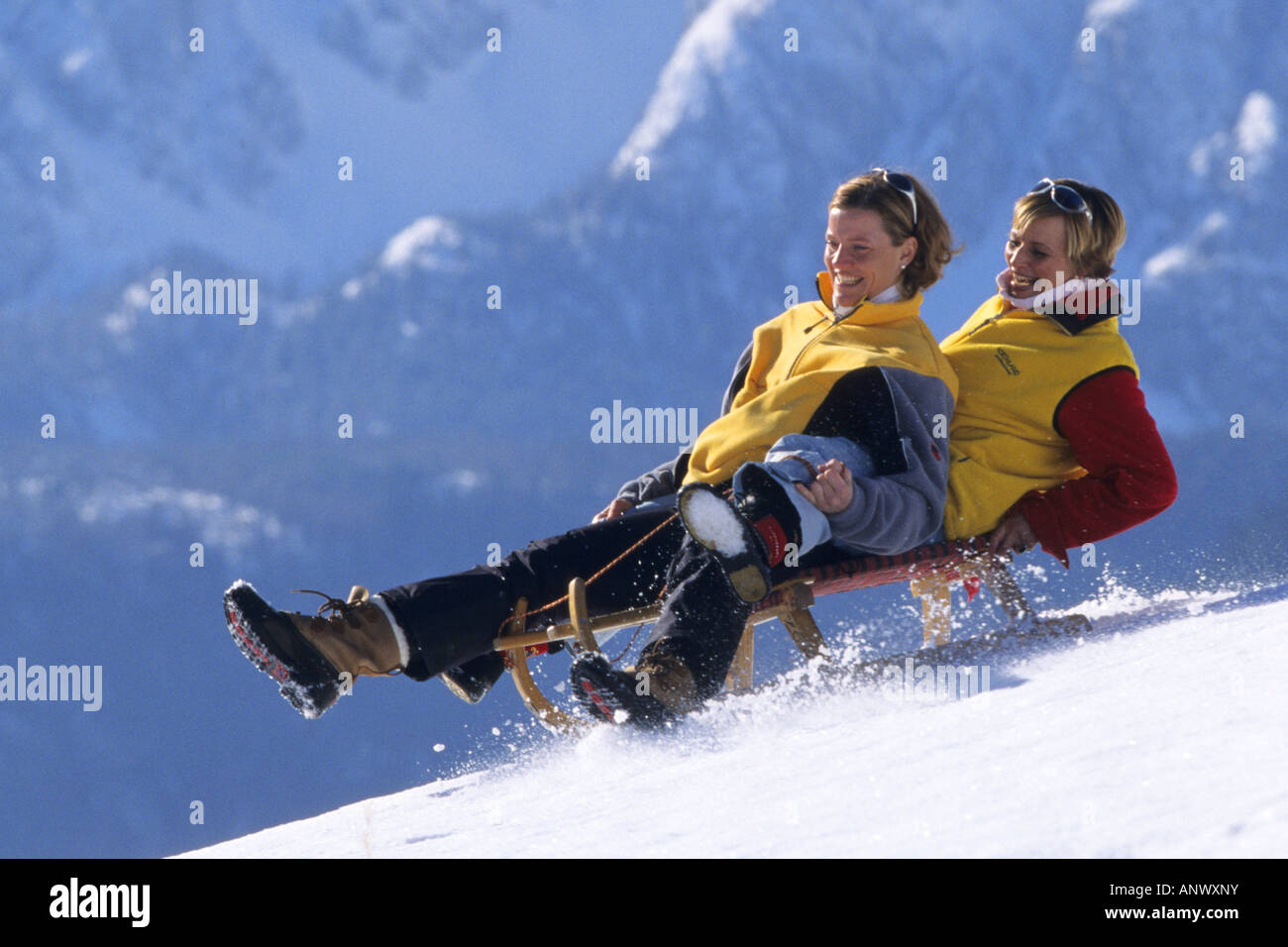 Two young women on a toboggan in the alps hi-res stock photography and ...