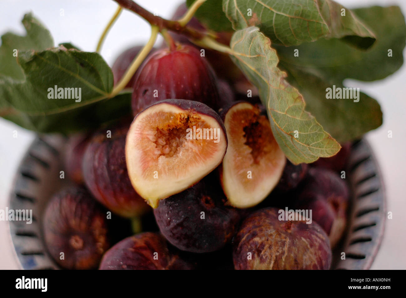 Whole and cut Figs in an hand thrown ceramic bowl with fig leaves Stock ...