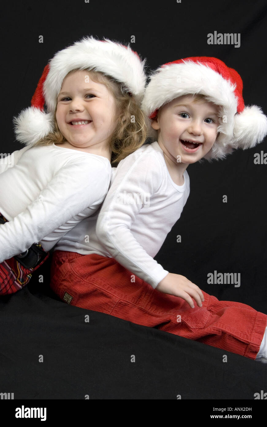 christmas boy and girl with santa claus cap in front of black ...