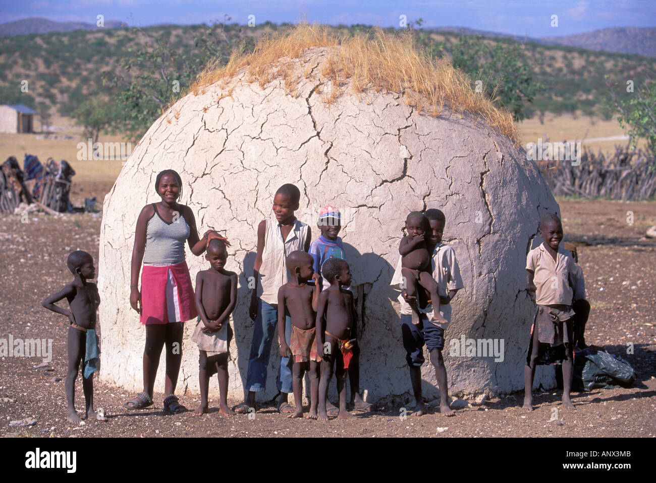 Children standing infront of a traditional mud hut in the Himba village ...
