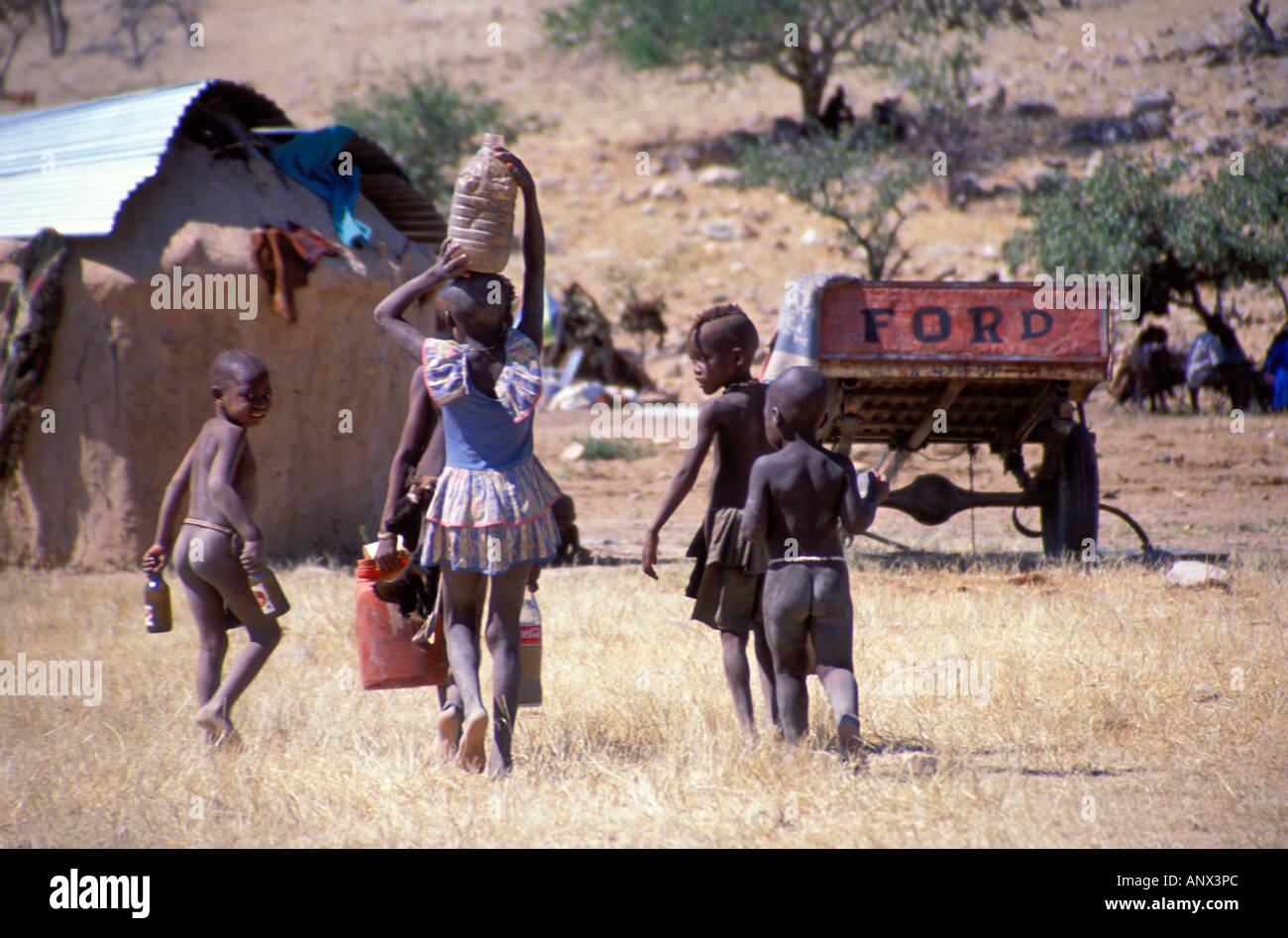 Village children carrying water in the rural Himba village of Okohimu ...
