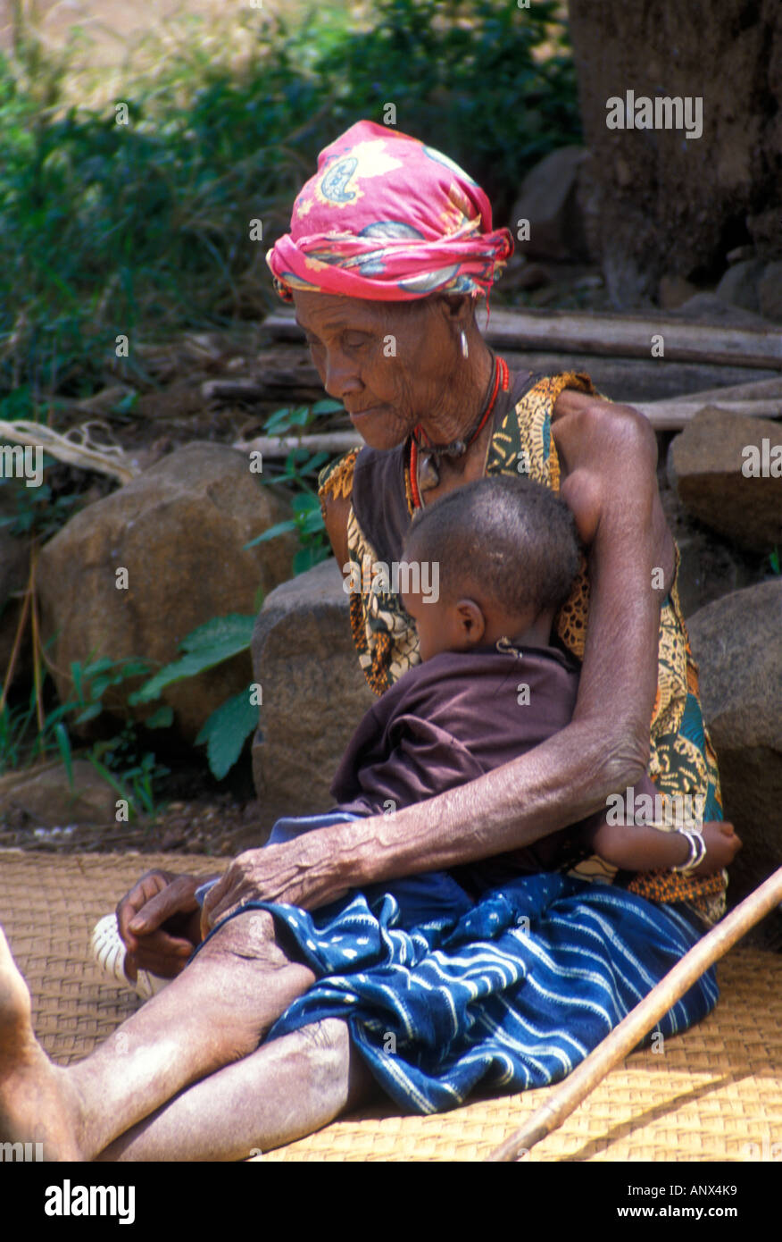 Grandmother with young boy in her lap sits on mat in traditional Bedik ...