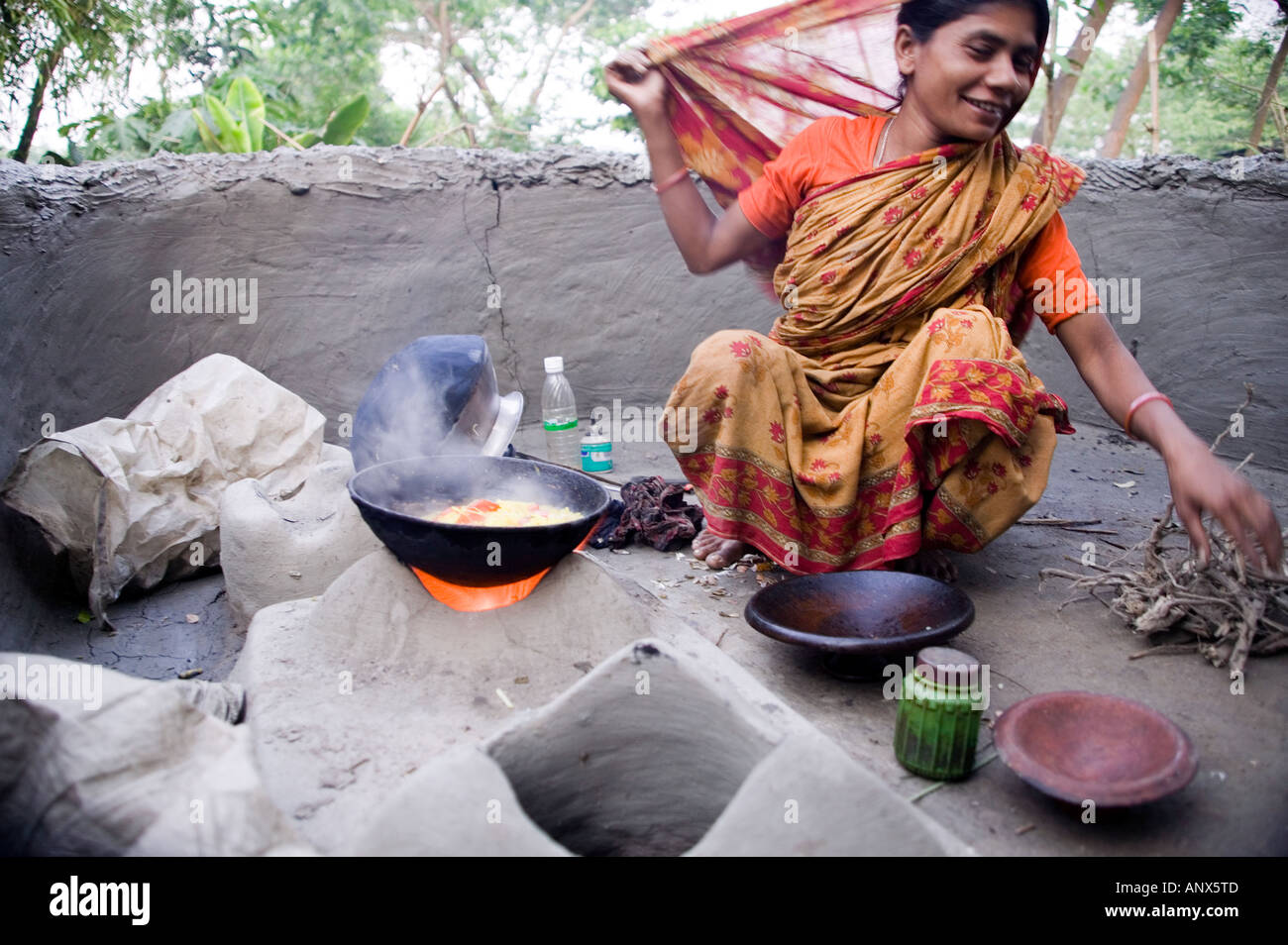 Woman cooking breakfast using a mud stove in a village in Bangladesh ...