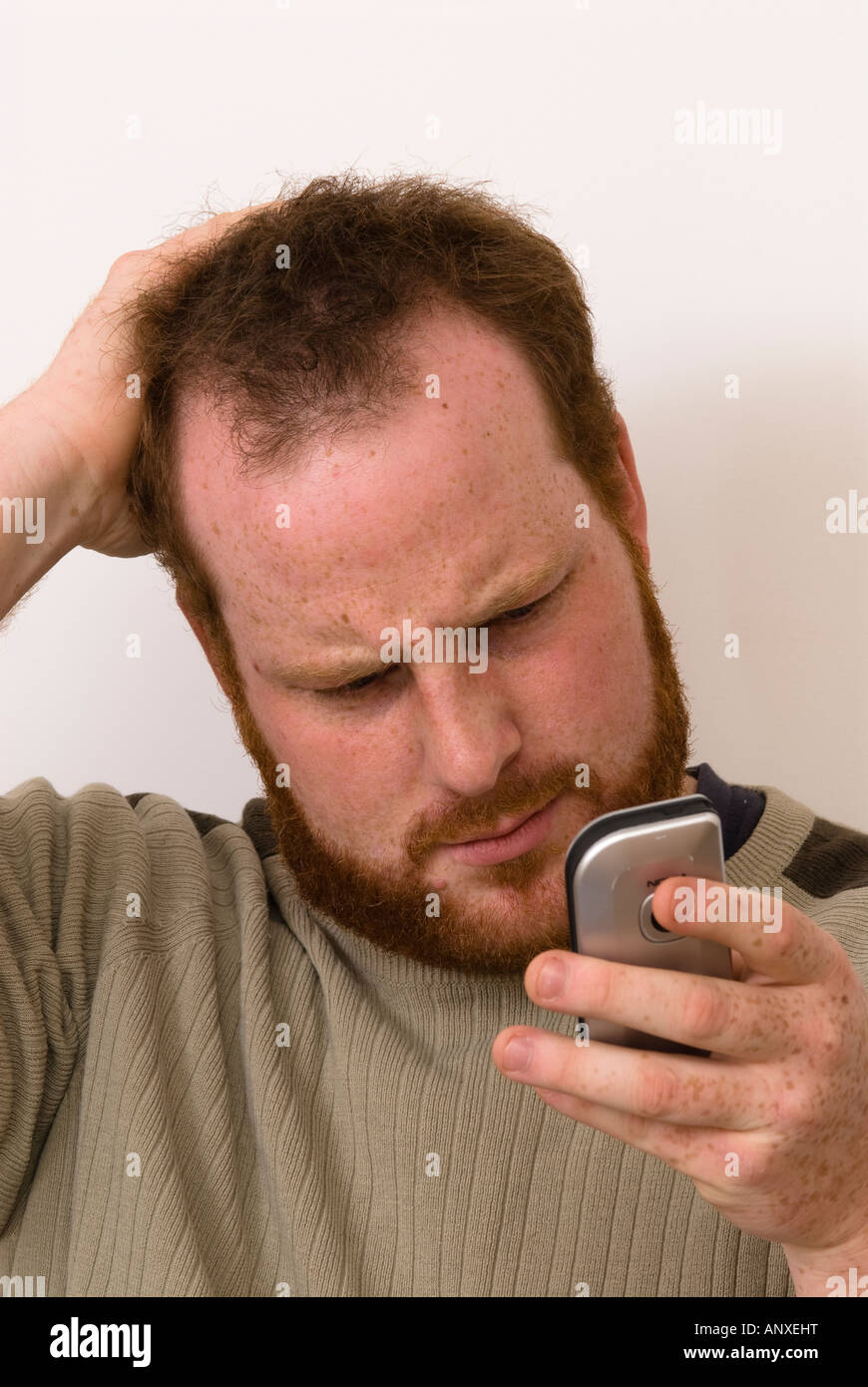man looking at mobile phone with a concerned worried look on his face ...