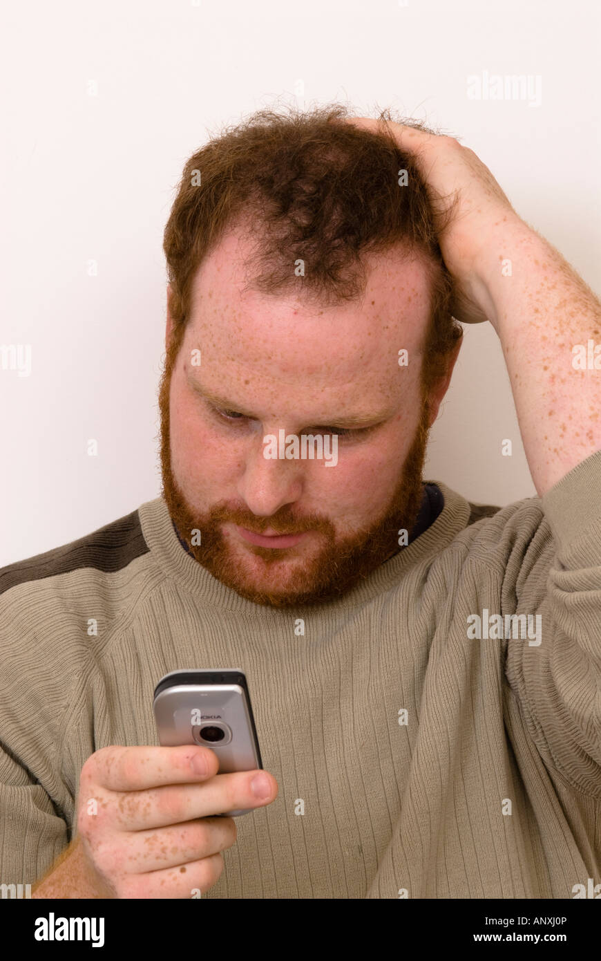 man looking at mobile phone with a concerned worried look on his face ...