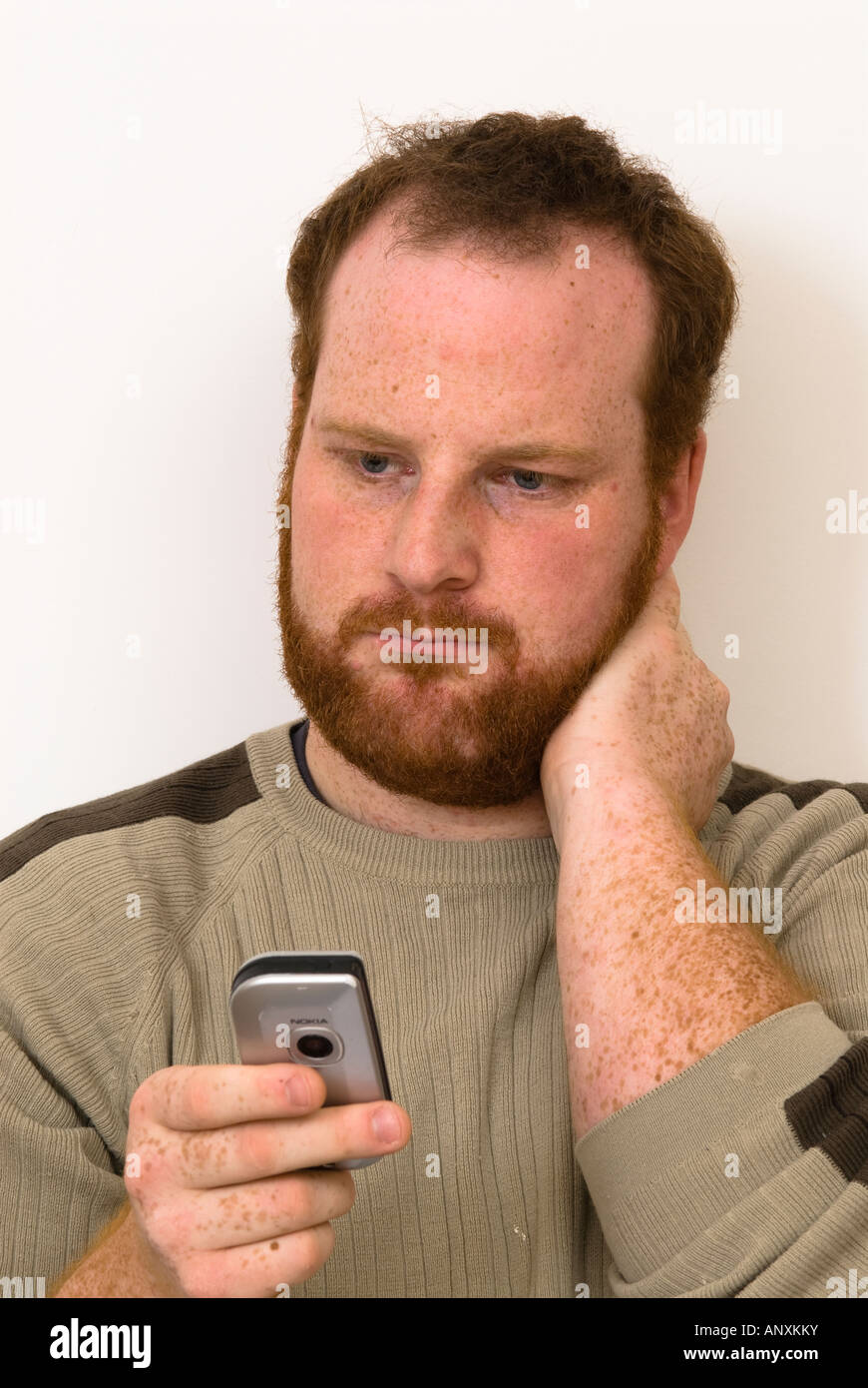 man looking at mobile phone with a concerned worried look on his face ...