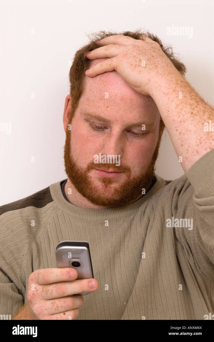 man looking at mobile phone with a concerned worried look on his face ...