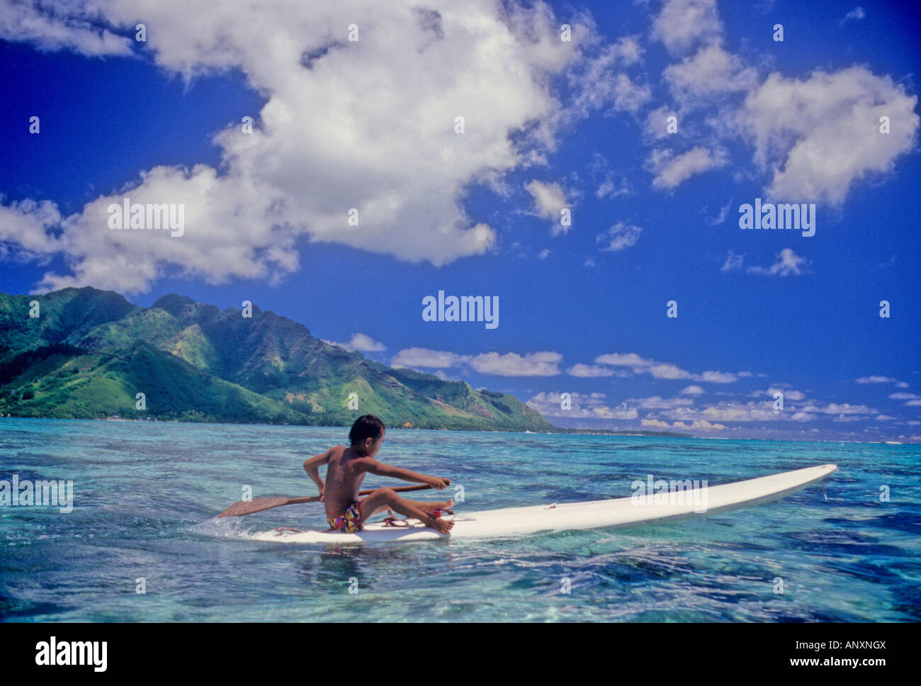 Boy paddles off Moorea Stock Photo - Alamy