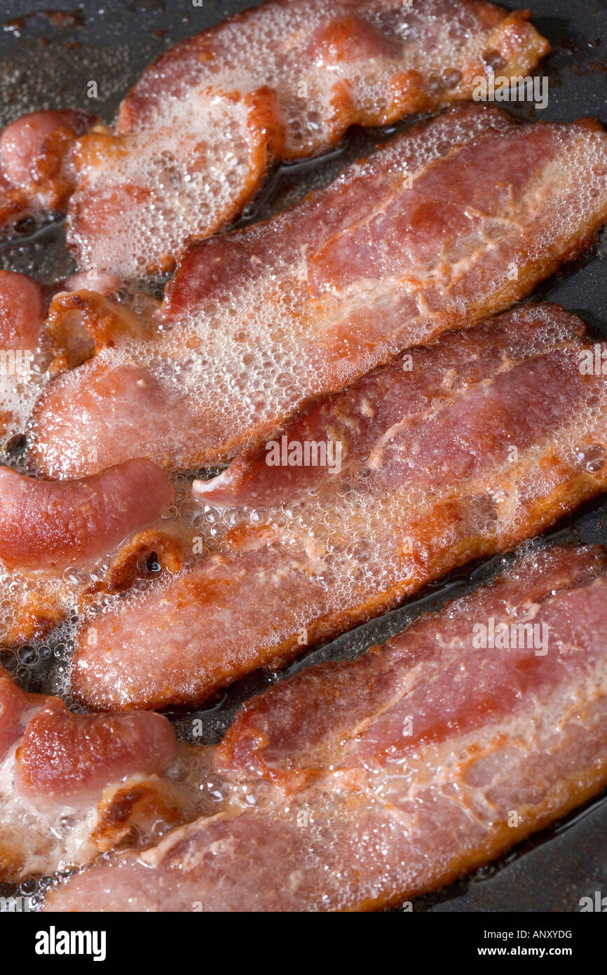 cooking bacon close up showing glistening sizzling boiling fat Stock ...