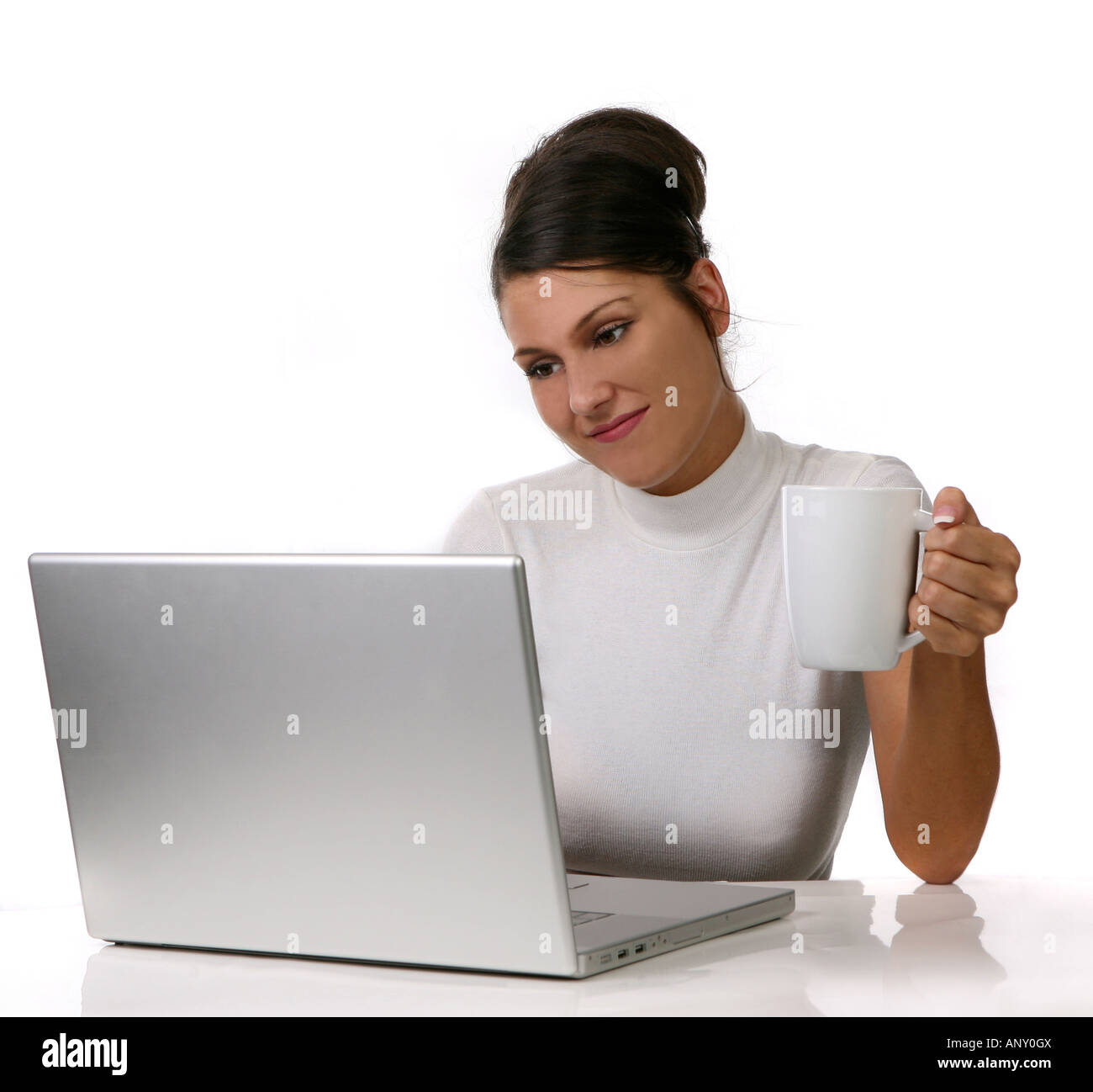 Young woman looks at her laptop computer and drinks her coffee on White ...