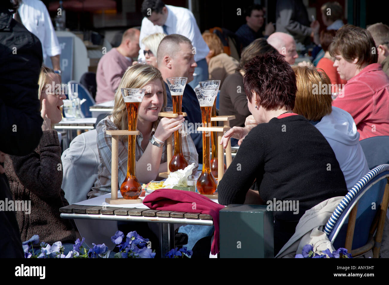 Belgium, Bruges. A crowd enjoys a glass of Beer, served in the ...